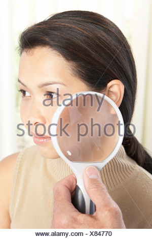 Dermatological examination. Dermatologist using a magnifying glass to ...