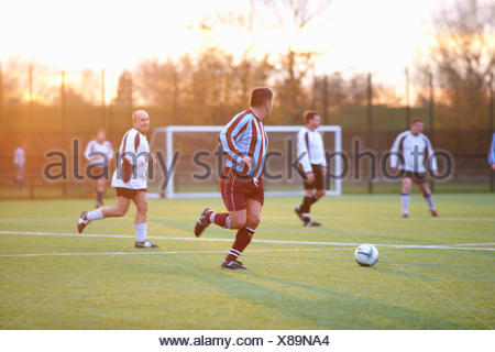 Football players running after ball Stock Photo - Alamy