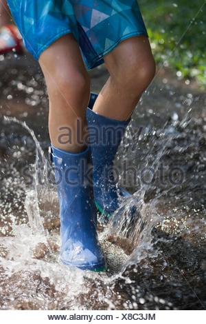 Boy in wellies splashing in puddle of water Stock Photo: 102578725 - Alamy
