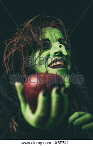 Green witch with dark hood smiling. Halloween makeup Stock Photo - Alamy