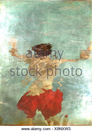 A teenager floating face down in a swimming pool wearing red shorts ...