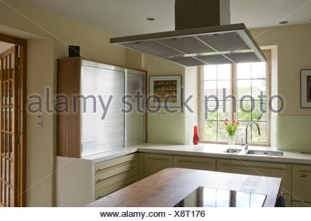 Extractor fan above central island unit with ceramic hob in modern ...