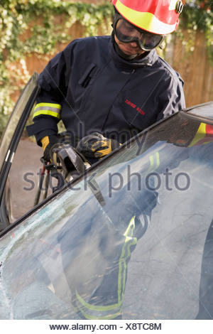 Firefighter cutting out a windshield after an accident with injured ...