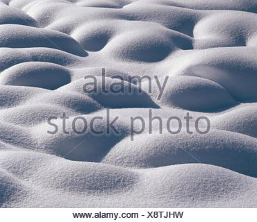 Fresh hilly snow surface background and drifting snowflakes. Bumpy ...