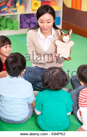 Female teacher playing hand puppet game with cute kindergarten Stock ...