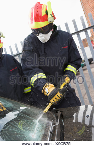 Firefighter cutting out a windshield after an accident with injured ...