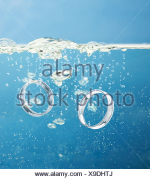 Studio shot of silver wedding rings falling into water Stock Photo - Alamy