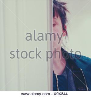 Young woman hiding behind a wall Stock Photo - Alamy