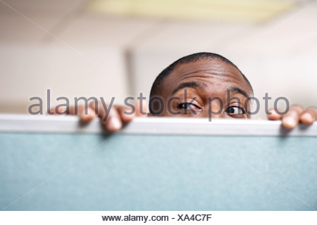 Businessman peeking over cubicle wall Stock Photo - Alamy