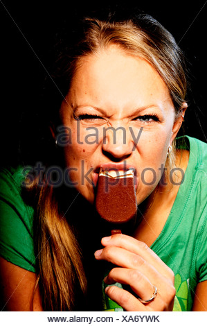 A young woman biting into a chocolate magnum ice cream Stock Photo - Alamy