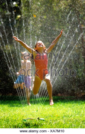 Girl jumping through lawn sprinkler Stock Photo: 29727092 - Alamy