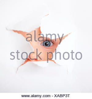 baby peering through hole in a white paper surface with one eye Stock ...