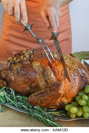Man carving a turkey at a Thanksgiving table set with formal dinnerware ...
