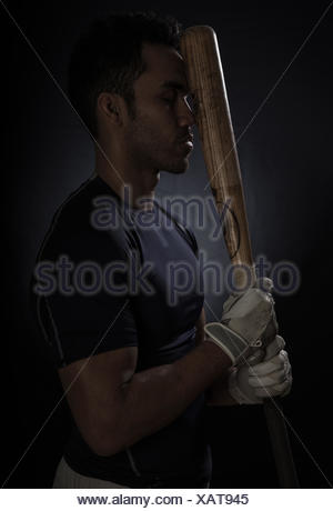 Baseball player holding bat, looking over shoulder Stock Photo ...