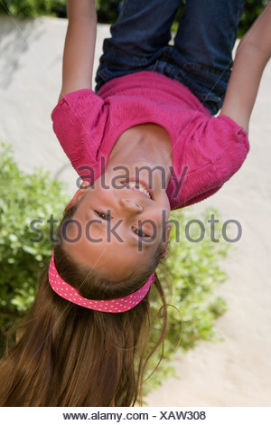 Little girl upside down hanging from trapeze monkey bars Stock Photo: 50490018 - Alamy