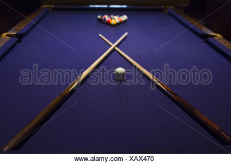 Pool cue sticks, a cue ball and a rack of balls ready for a game of ...