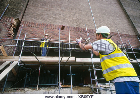 Two construction workers throwing bricks, United Kingdom Stock Photo ...