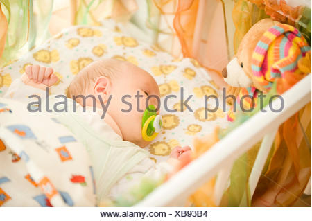 Baby girl with pacifier inside crib Stock Photo: 87249502 - Alamy