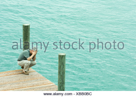 Man crouching holding head, side view Stock Photo: 25022677 - Alamy