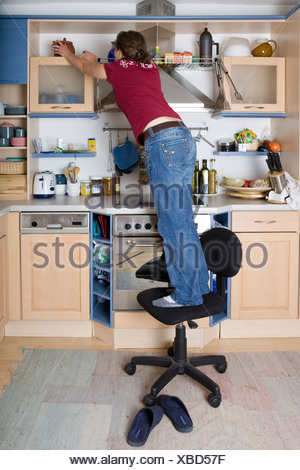 Household accidents, girl standing on a chair in the kitchen, tilting ...