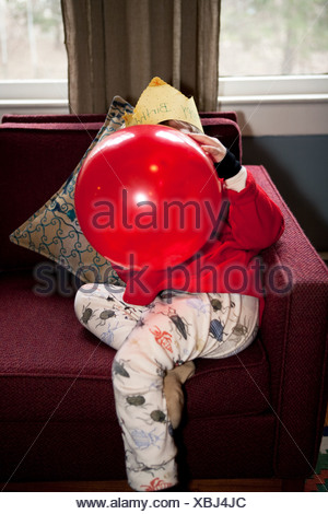 boy 7 blowing up a red balloon for a birthday party looking wide eyed ...