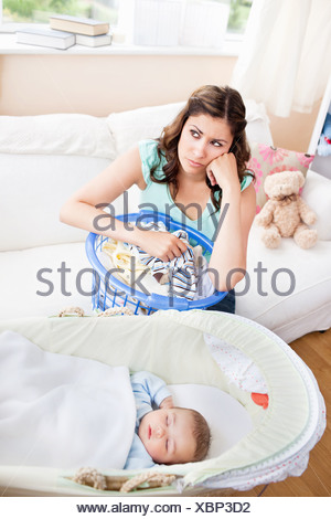 Bored mother waiting for her baby to wake-up sitting in the sofa with ...