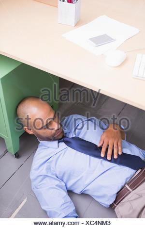 Businessman sleeping under desk Stock Photo: 20581588 - Alamy
