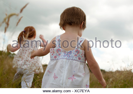 Two little girls (sisters) walking away hand in hand. Wearing Stock ...