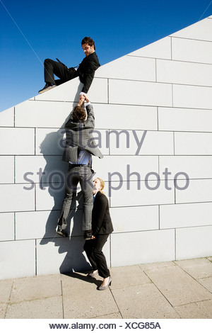 A young man climbing over a wall Stock Photo - Alamy