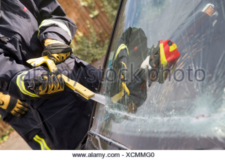 Firefighter cutting out a windshield after an accident with injured ...