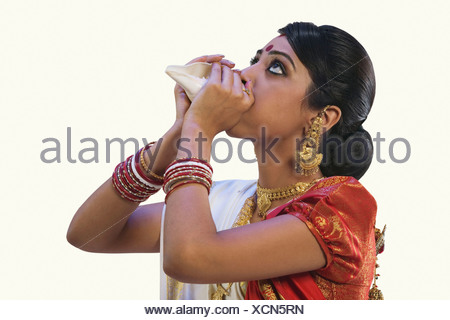 Bengali woman blowing on a conch shell Stock Photo - Alamy