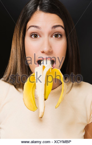 Young woman biting into a banana Stock Photo - Alamy