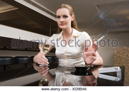 Woman drinking a glass of wine and smoking a cigarette Stock Photo - Alamy
