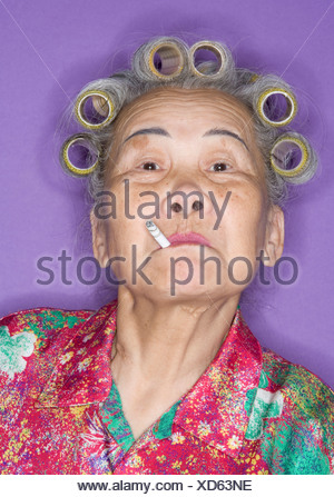 Portrait of woman with hair curlers smoking a cigarette while talking ...
