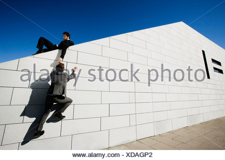 A young man climbing over a wall Stock Photo - Alamy