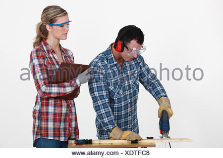 Man using band saw whilst woman supervises Stock Photo - Alamy