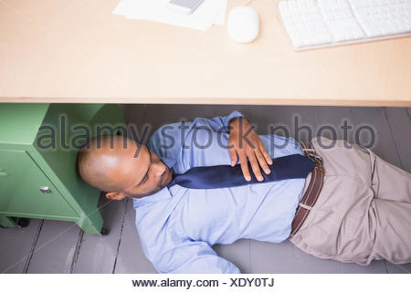 Businessman sleeping under desk Stock Photo: 20581588 - Alamy