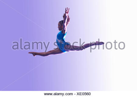 Gymnast posing in mid air against a white background. She is wearing ...