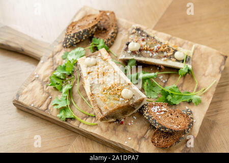 Gebratenes Knochenmark serviert mit Toast und Petersilie und Zwiebeln ...