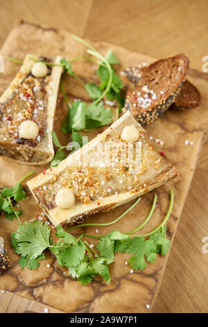 Gebratenes Knochenmark serviert mit Toast und Petersilie und Zwiebeln ...