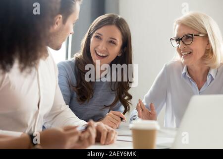 Freundliche Kollegen unterhalten sich, während sie im Büro sitzen, und der vielversprechende ...