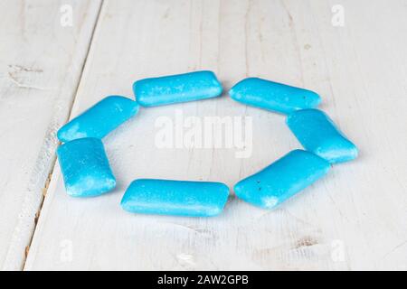 Gruppe von sieben ganzen blauen Kaugummis isoliert auf schwarzem Glas ...