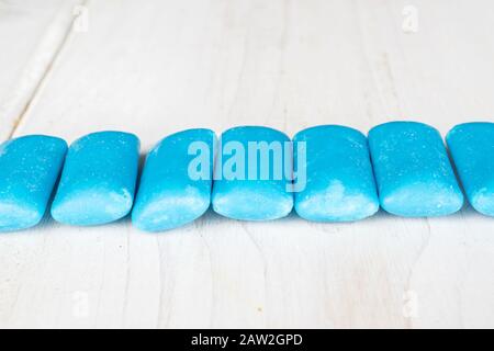 Gruppe von sieben ganzen blauen Kaugummis isoliert auf schwarzem Glas ...