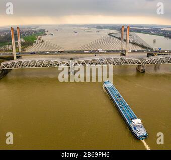 Konkrete Brücke über Wasser mit einer Bahn und Straße, die parallel und ...