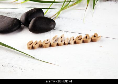 Wellness-Schild mit Holzbuchstaben mit Blättern und Steinen. Relax ...