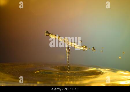 Fallende Wassertropfen vor farbigem Hintergrund bilden eine Form ...