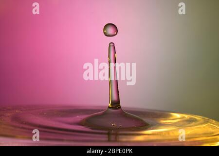 Fallende Wassertropfen vor farbigem Hintergrund bilden eine Form ...