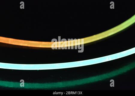 Ein Draht mit orangefarbenem und grünem Licht, ein Lichtleiterkabel mit unterschiedlicher ...