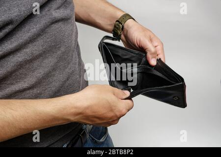 Der Mensch schaut auf eine leere Geldbörse ohne Geld.Es gibt keine ...