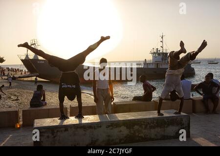 Kinder machen Gymnastik am Strand in Stone Town, abends und morgens ...